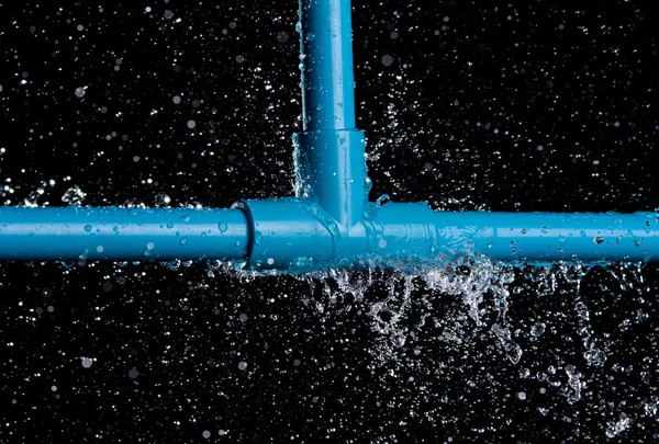 leaked and splash water from pvc plastic pipe over a black background ...