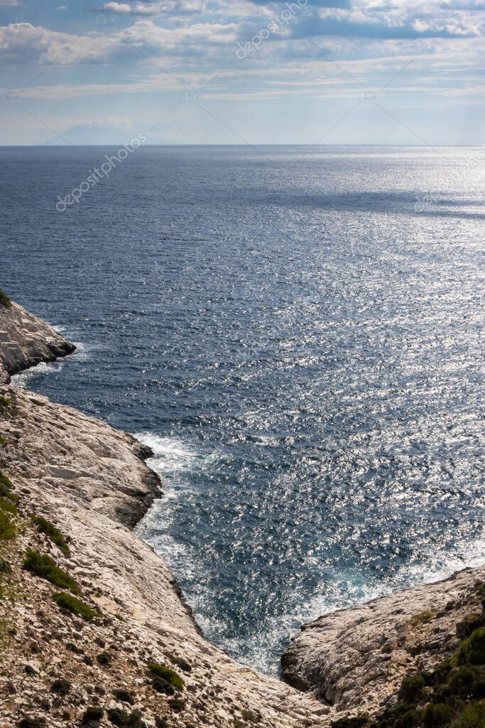 La roca y el mar. Agua tranquila, color azul oscuro. Cielo azul con ...