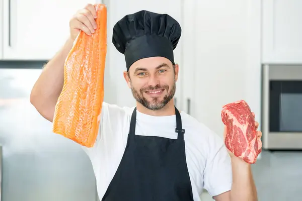 Man chef cooker hold fish and meat, salmon and beef. Male chef in chefs ...