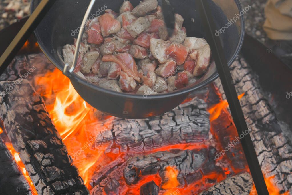 Trozos de carne en un caldero sobre carbones en llamas background.food ...