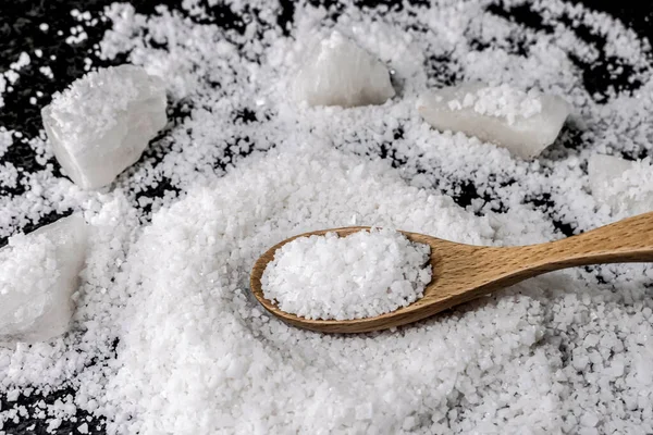 A spoonful of rock salt on the kitchen counter. Isolated on black and ...
