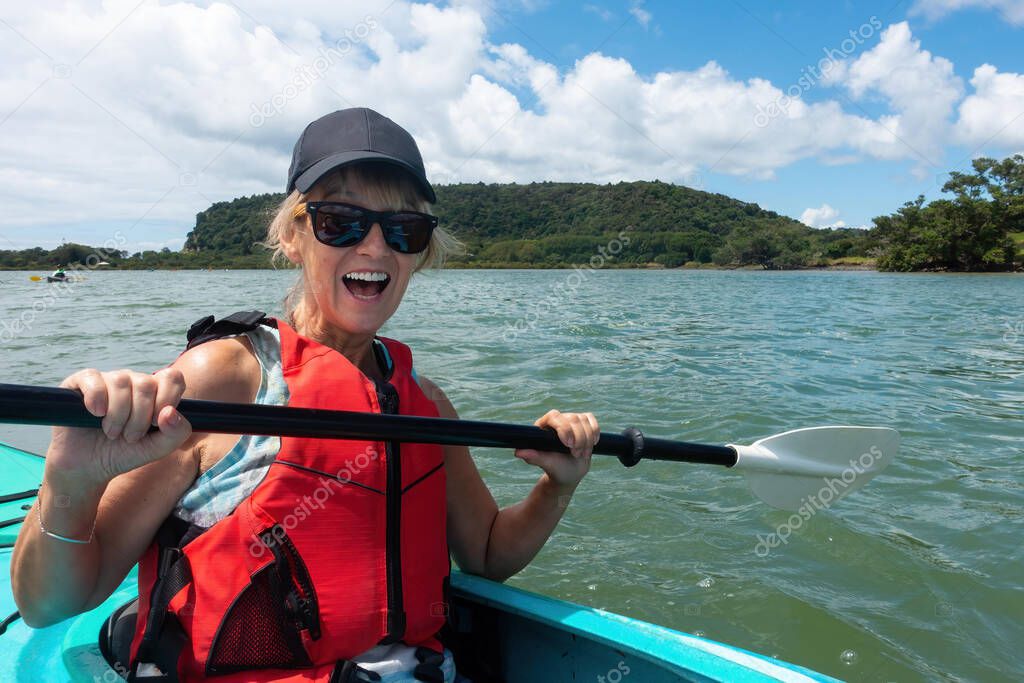 A lady in her 60's sat in a canoe smiling and laughing looking very ...