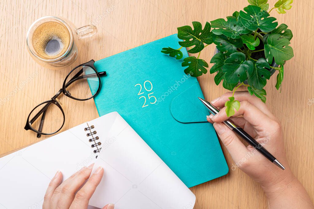 Resoluciones de año nuevo 2025 en el escritorio. 2025 metas - manos y cuaderno, taza de café ...