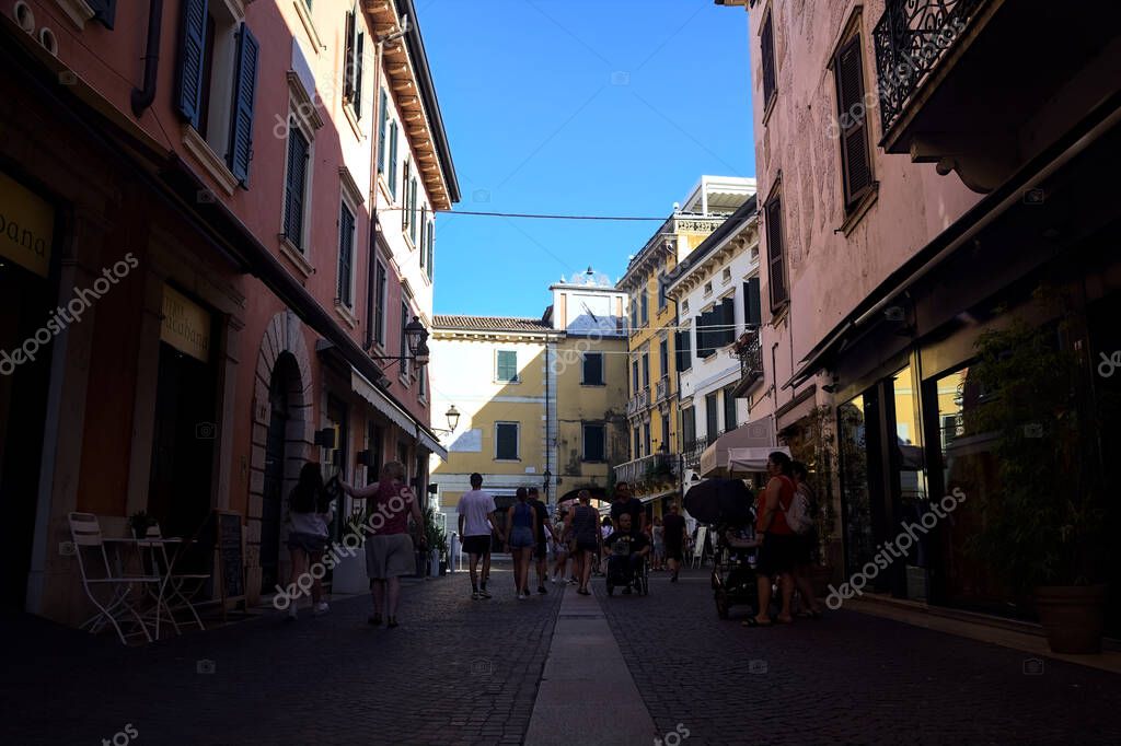 Calle empedrada estrecha con tiendas y gente que pasa por un pueblo ...