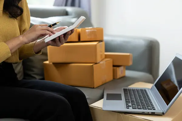 Beautiful Asian startup owner at home with laptop and package boxes in ...