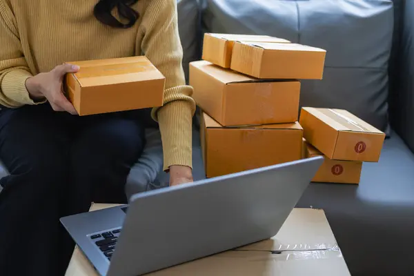 Beautiful Asian startup owner at home with laptop and package boxes in ...