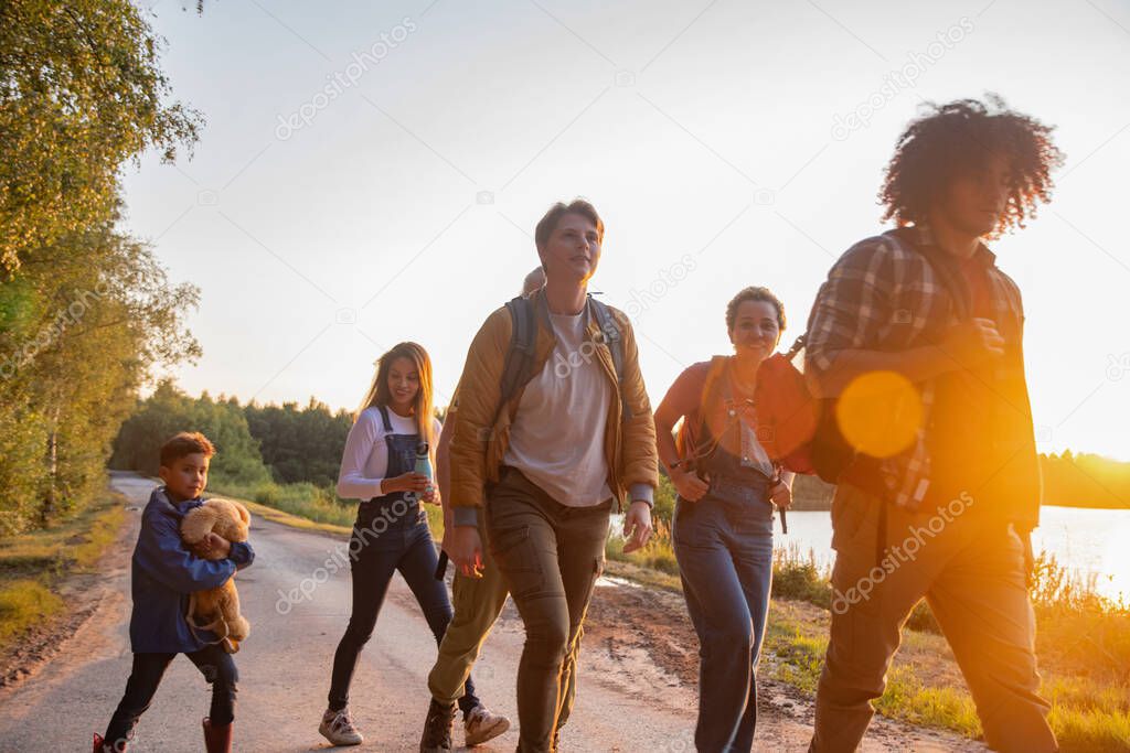 Un grupo de amigos, niños y niñas, turistas con un niño pequeño caminar ...