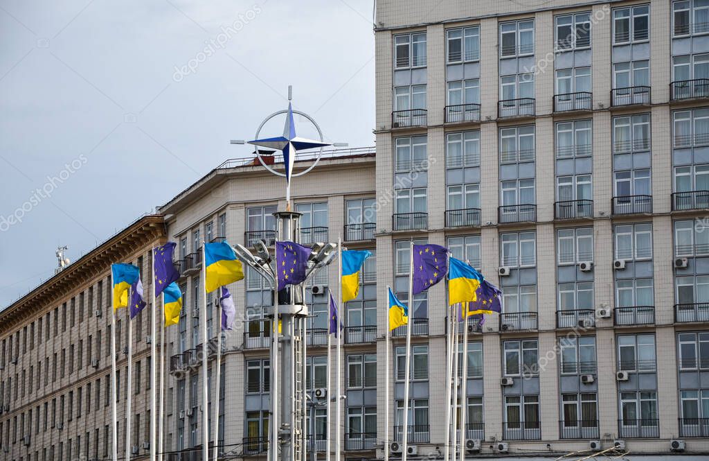 Flags of Ukraine and the European Union waving together under emblem of ...