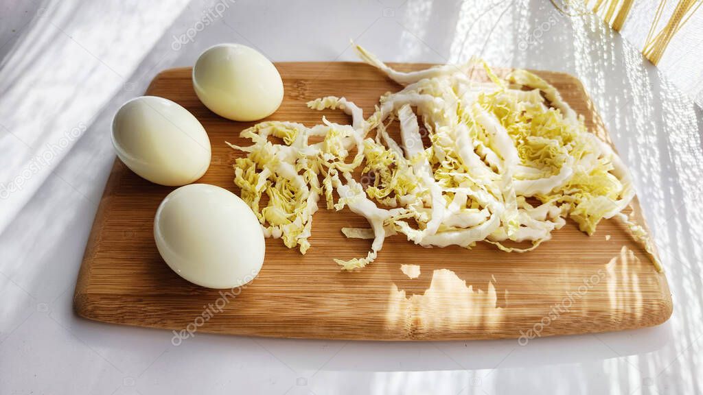 Repollo de Pekín picado y huevos pelados en la tabla de cortar como ...