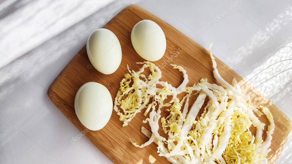 Repollo de Pekín picado y huevos pelados en la tabla de cortar como ...