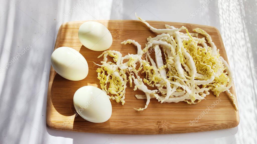 Repollo de Pekín picado y huevos pelados en la tabla de cortar como ...