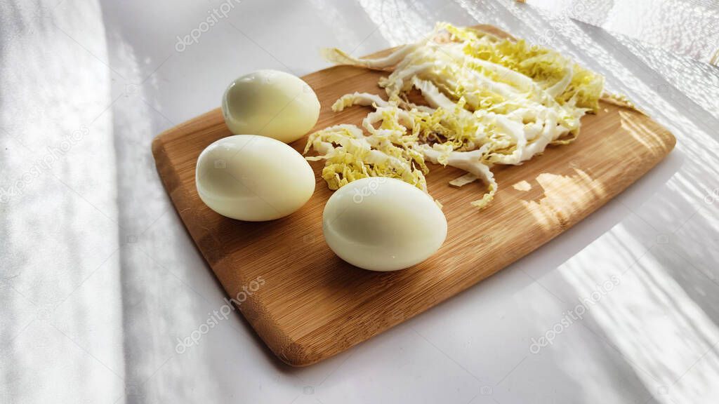 Repollo de Pekín picado y huevos pelados en la tabla de cortar como ...