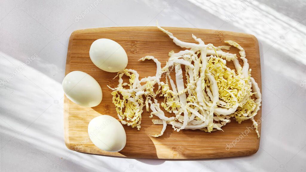 Repollo de Pekín picado y huevos pelados en la tabla de cortar como ...