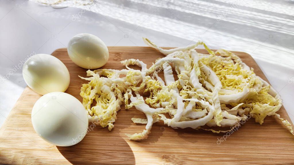 Repollo de Pekín picado y huevos pelados en la tabla de cortar como ...