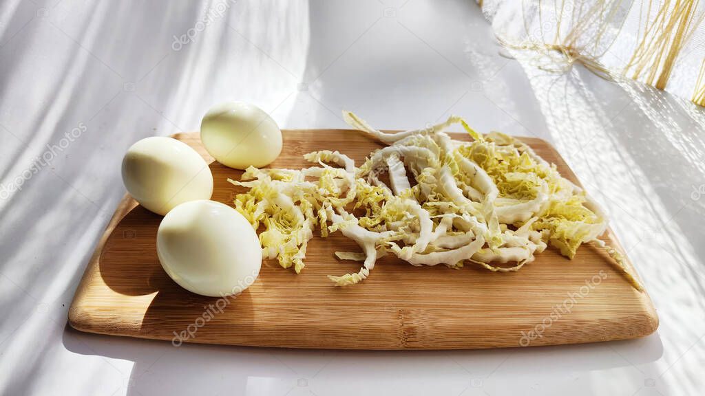 Repollo de Pekín picado y huevos pelados en la tabla de cortar como ...