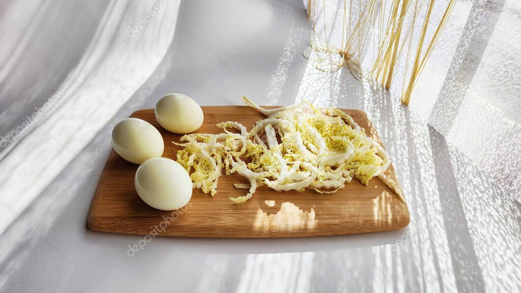 Repollo de Pekín picado y huevos pelados en la tabla de cortar como ...
