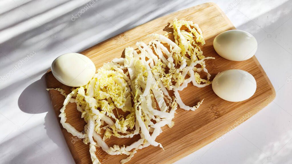 Repollo de Pekín picado y huevos pelados en la tabla de cortar como ...