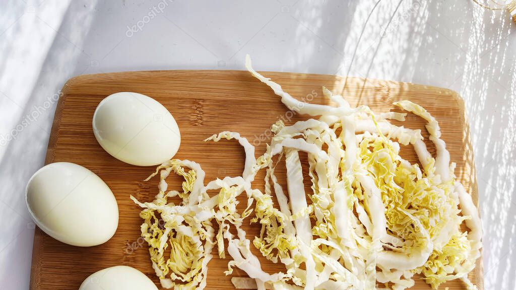 Repollo de Pekín picado y huevos pelados en la tabla de cortar como ...