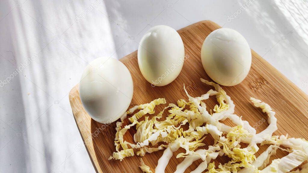 Repollo de Pekín picado y huevos pelados en la tabla de cortar como ...