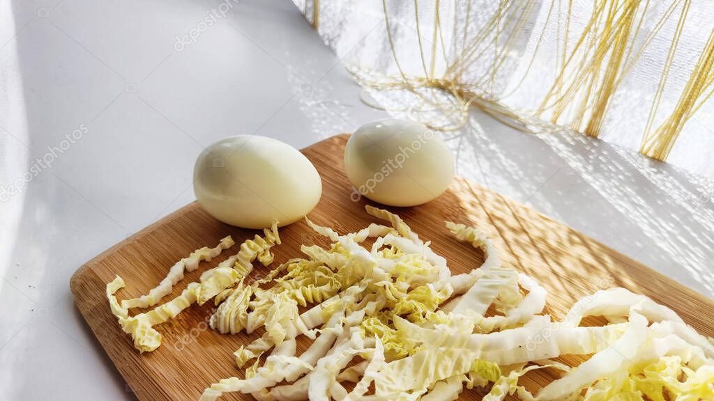Repollo de Pekín picado y huevos pelados en la tabla de cortar como ...