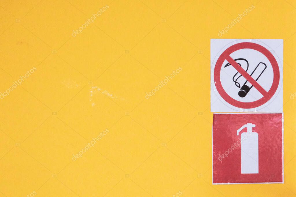 Cartel de fumar prohibido y extintor de incendios en la pared amarilla ...