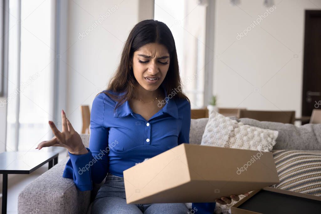 La mujer abre la caja de paquete de cartón recibida se siente confundida o decepcionada, se ...