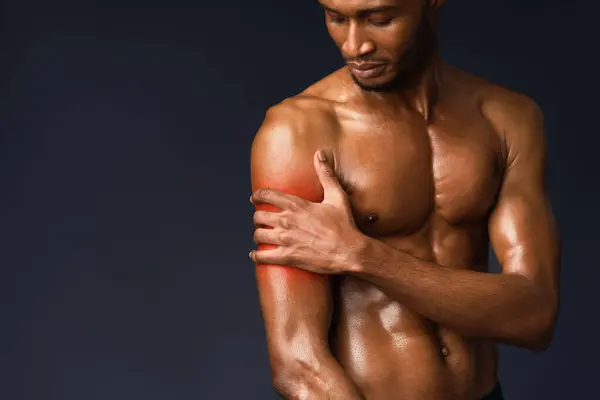Pain In The Shoulder. Muscular black bodybuilder touching hand with red ...