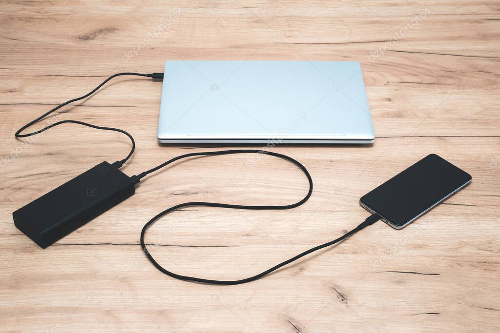 Banco de energía con cable USB-c está cargando el ordenador portátil y ...