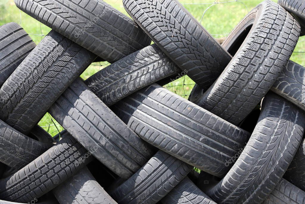 Neumáticos viejos en fila como una valla en un patio rural. Los ...