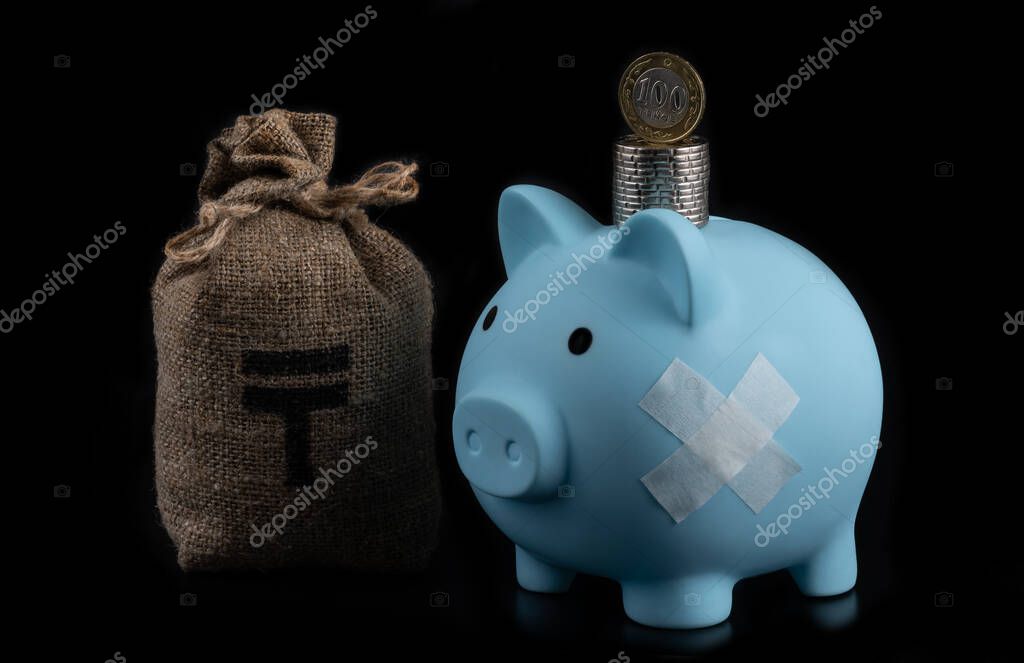 Hucha azul con monedas en denominaciones de 100 tenge kazajo sobre ...