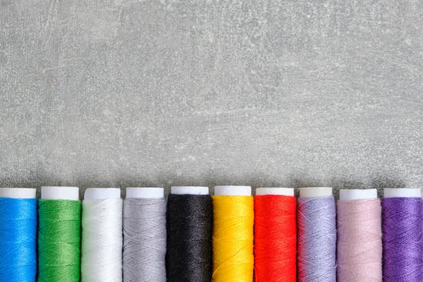 Reels with multi colored sewing threads gray concrete background ...