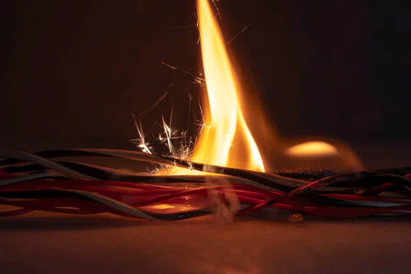 Ignition and fire in electrical wires on a dark background. A short ...