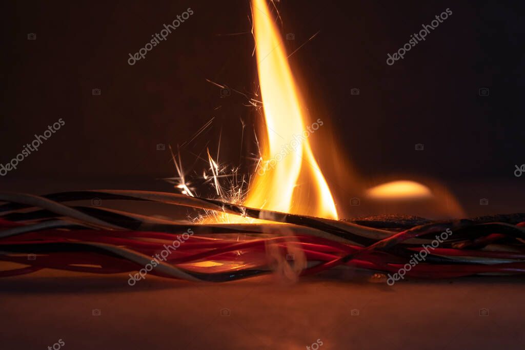 Ignition and fire in electrical wires on a dark background. A short ...