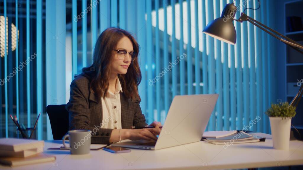 Una Empresaria Trabaja Tarde en una Oficina Moderna, Manteniendo una Atmósfera Positiva y ...