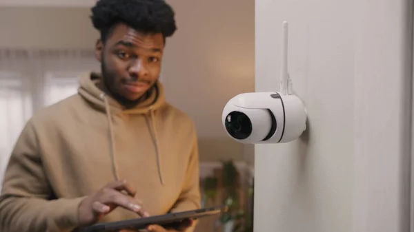 African American man installs security camera. Man sets up angle of ...