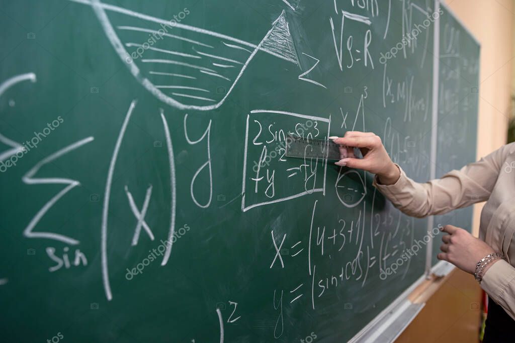 mano femenina con tiza y escribir fórmula matemática en pizarra ...