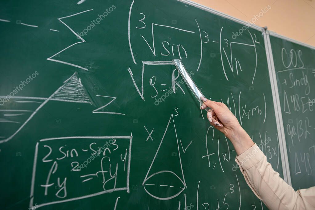 mano femenina con tiza y escribir fórmula matemática en pizarra ...