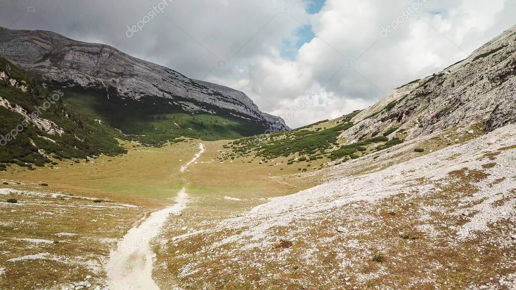 A gravelled pathway leading through Italian Dolomites. High, sharp ...