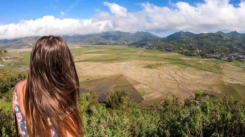 A woman in a jumpsuit admiring the colorful rice paddies forming a ...