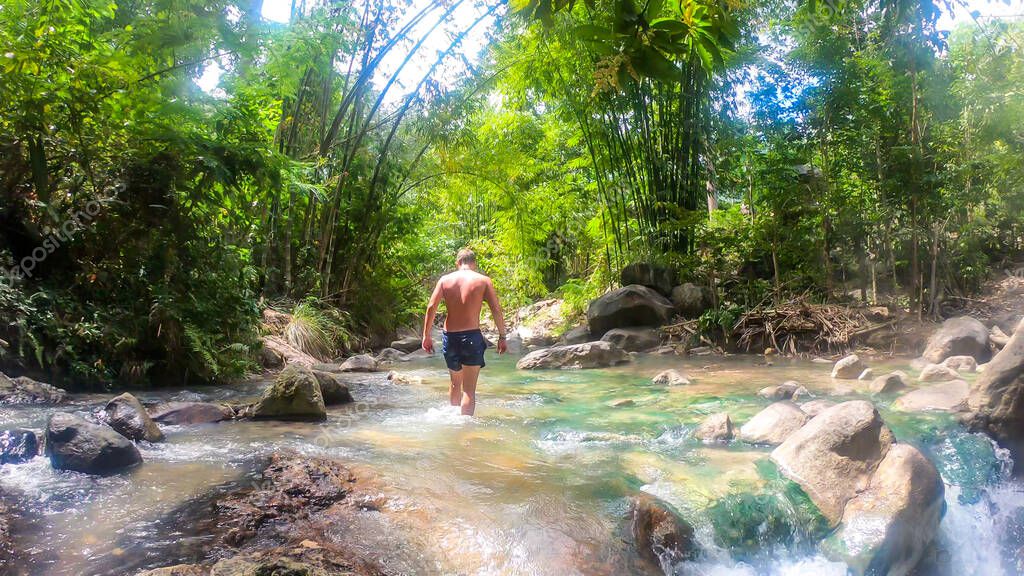 A young man walking at the cross section of hot spring merging with ...