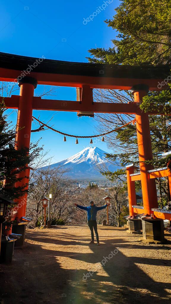 A man standing under the Torri gate, leading to Chureito Pagoda in ...