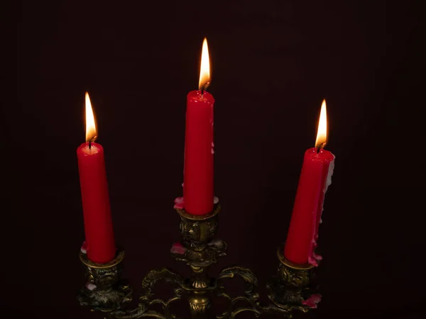 Burning red candles in a candlestick. Lighted candles in an old ...