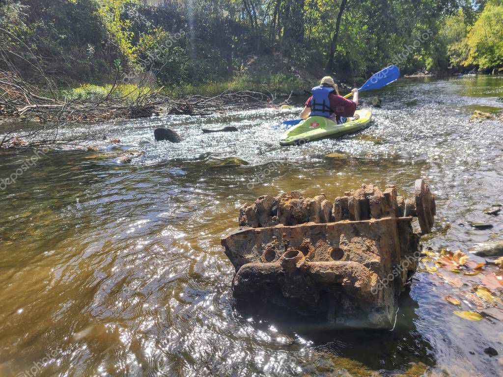 Un kayak en un vibrante kayak verde se desliza a lo largo de un río ...