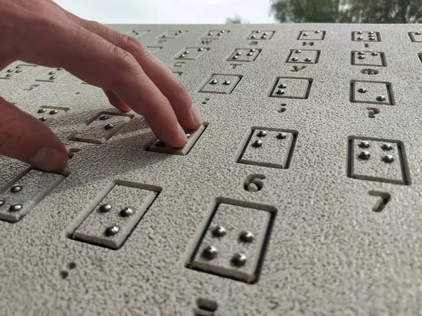 La mano de una persona con ceguera está leyendo el Braille al aire ...