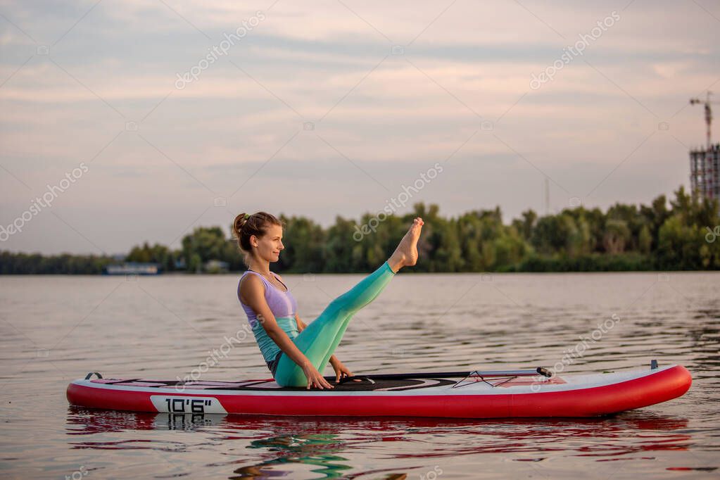 Mujer joven sentada sobre tabla de paddle, practicando yoga pose. Hacer ...
