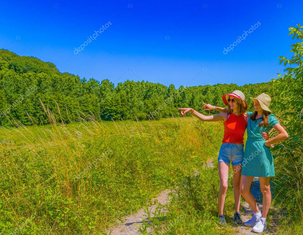 Dos chicas jóvenes mostrando la misma dirección al aire libre bajo el ...