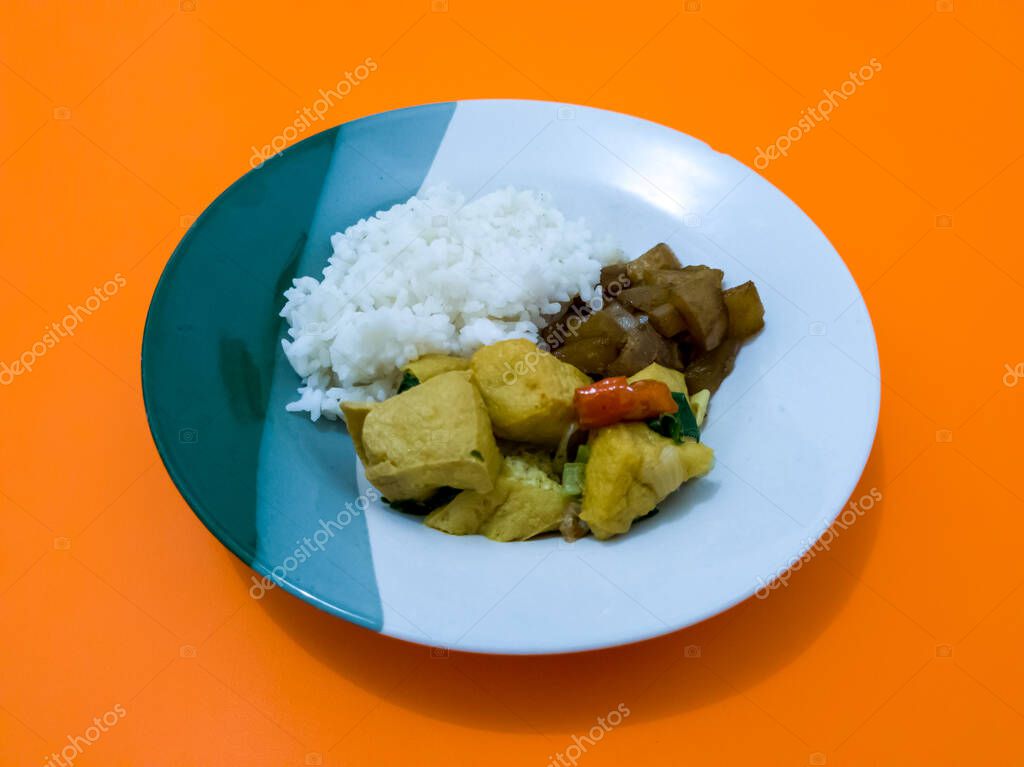 Arroz mezclado en un plato con guarniciones de tofu frito en rodajas y ...