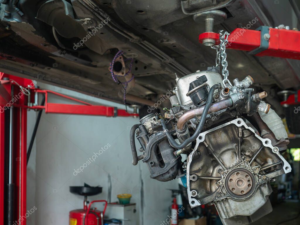 Motor de automóvil suspendido por una cadena en un garaje durante un ...