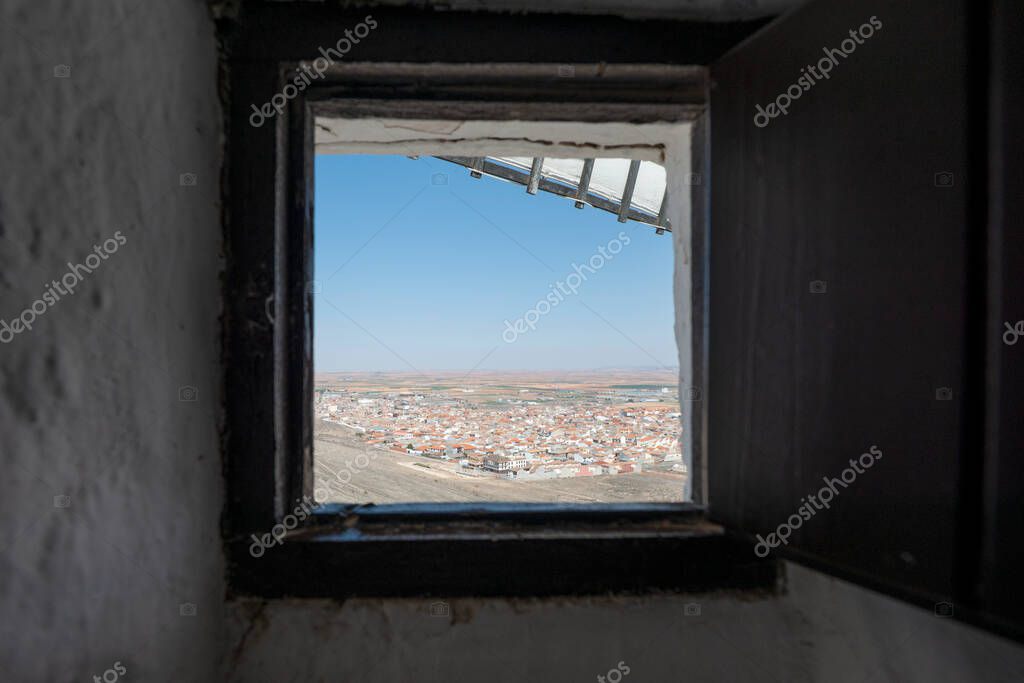 Square window of a windmill with blades and views of the town of ...