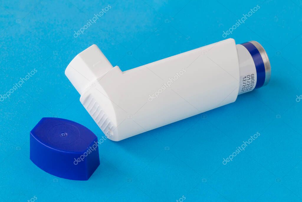 Inhalador de asma con etiqueta en blanco aislado sobre un fondo azul ...